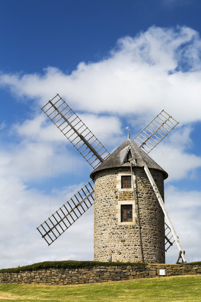 Latitude Run® An Old Stone Windmill On A Hillside With Wooden Blades ...